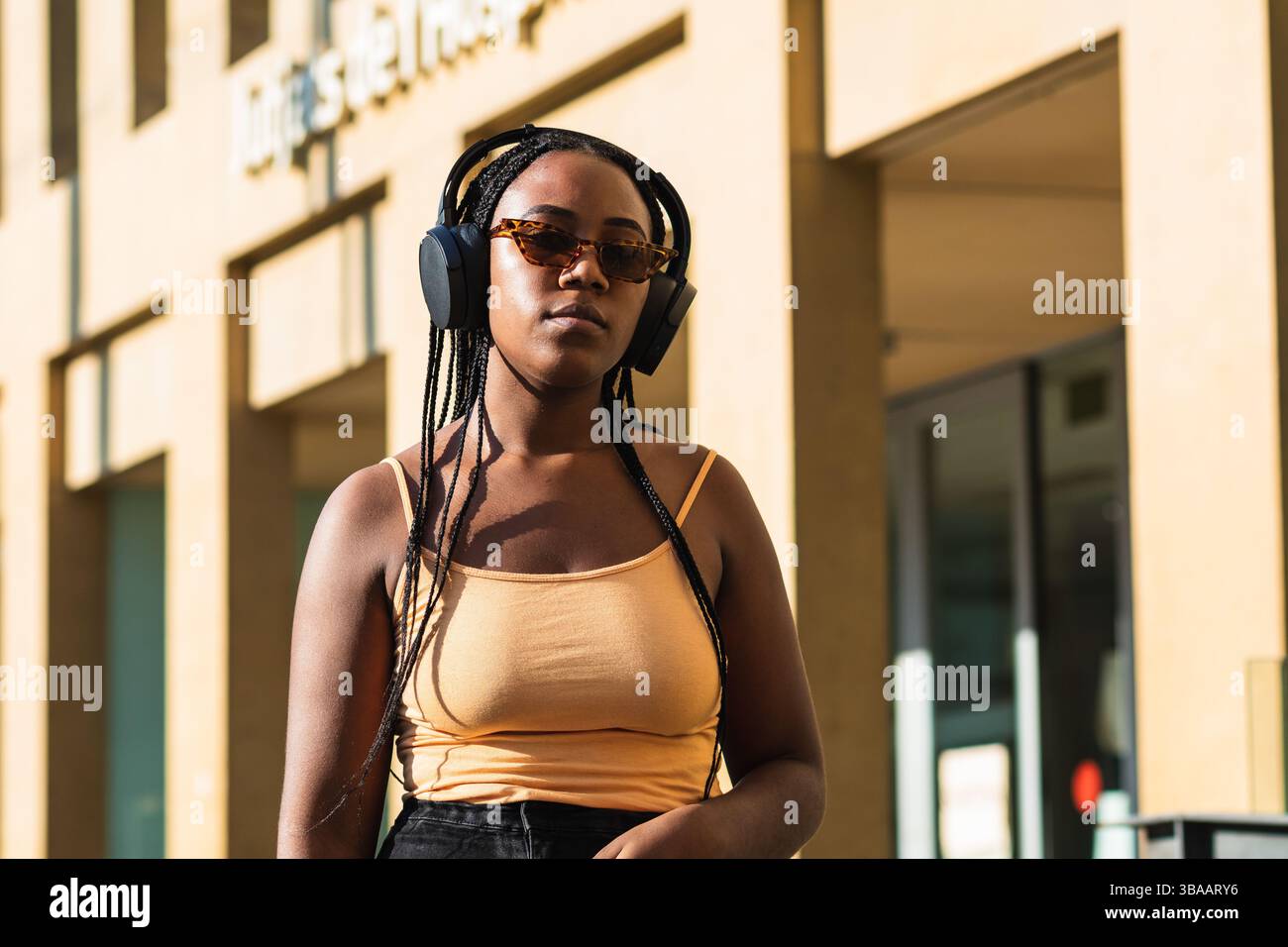 Serious black woman listening audio in the street Stock Photo - Alamy