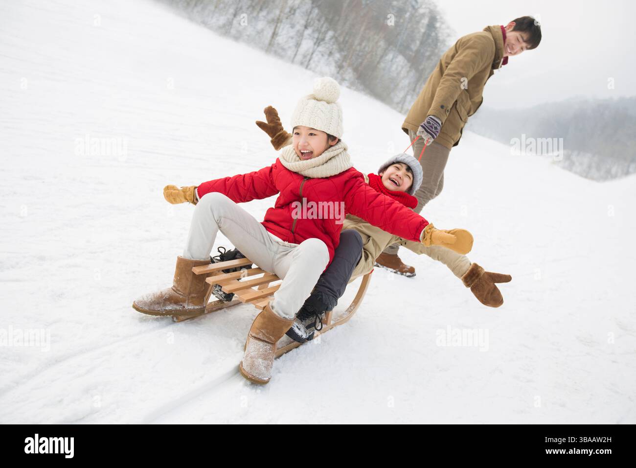 Young Chinese father pulling his children on sled Stock Photo - Alamy
