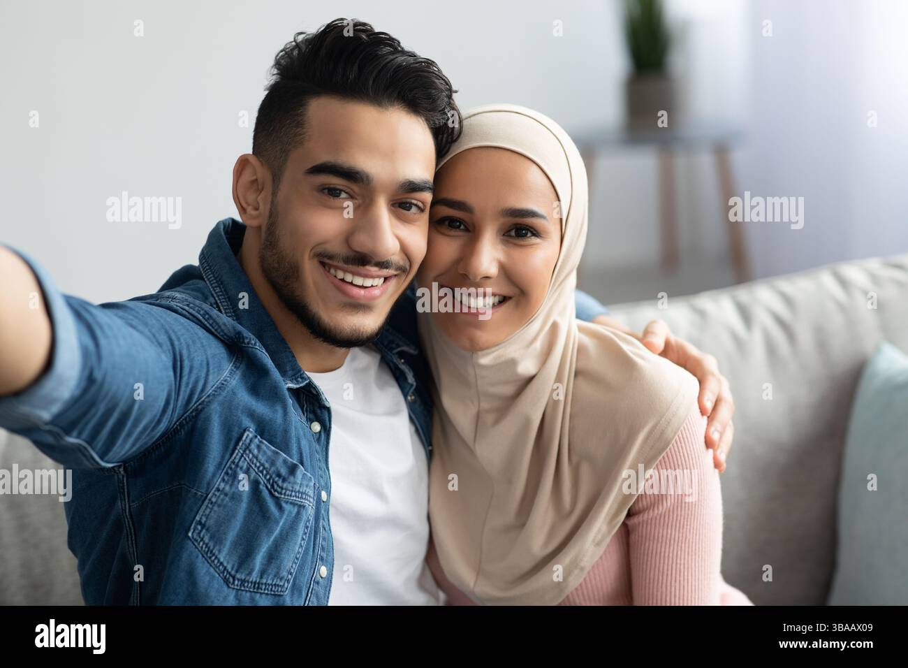 muslim man and woman in hijab taking selfie from home, copy space. Smiling middle eastern young ...