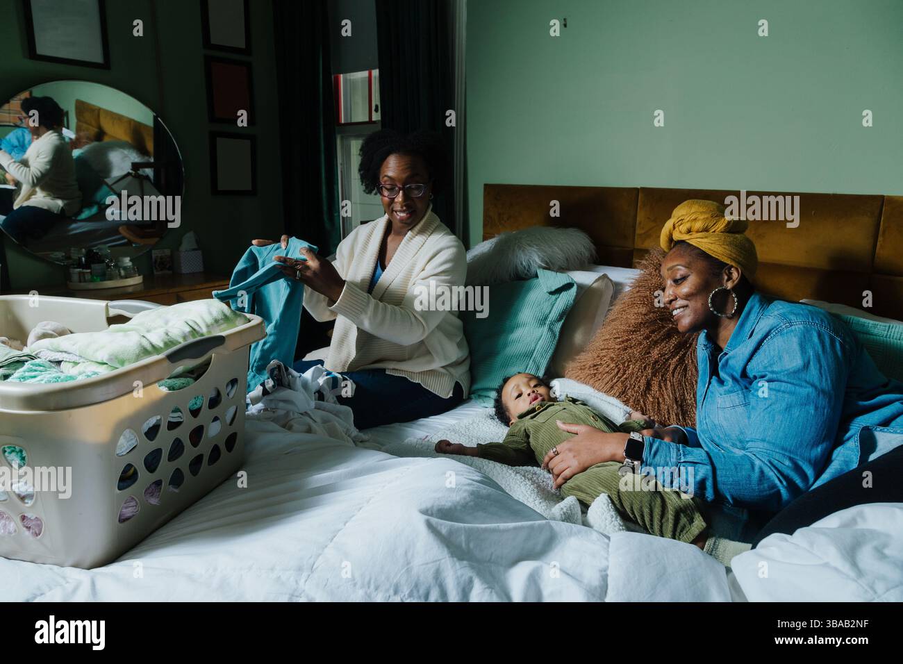 Black aunt folding clothes helping sister with baby while sitting on ...