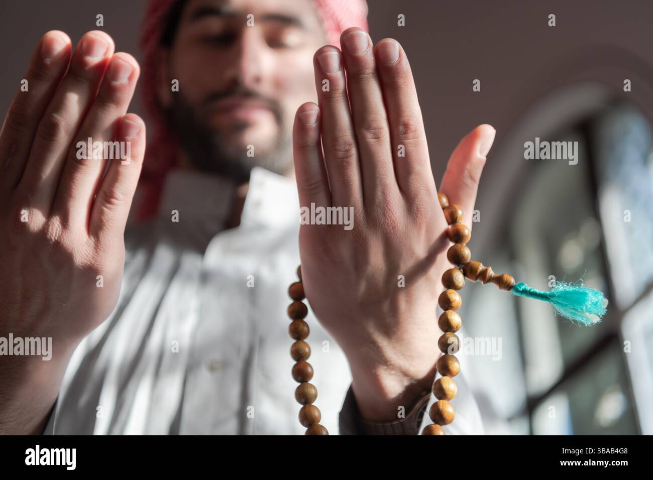 a Muslim with his arms raised performs and practices the Islamic prayer ...
