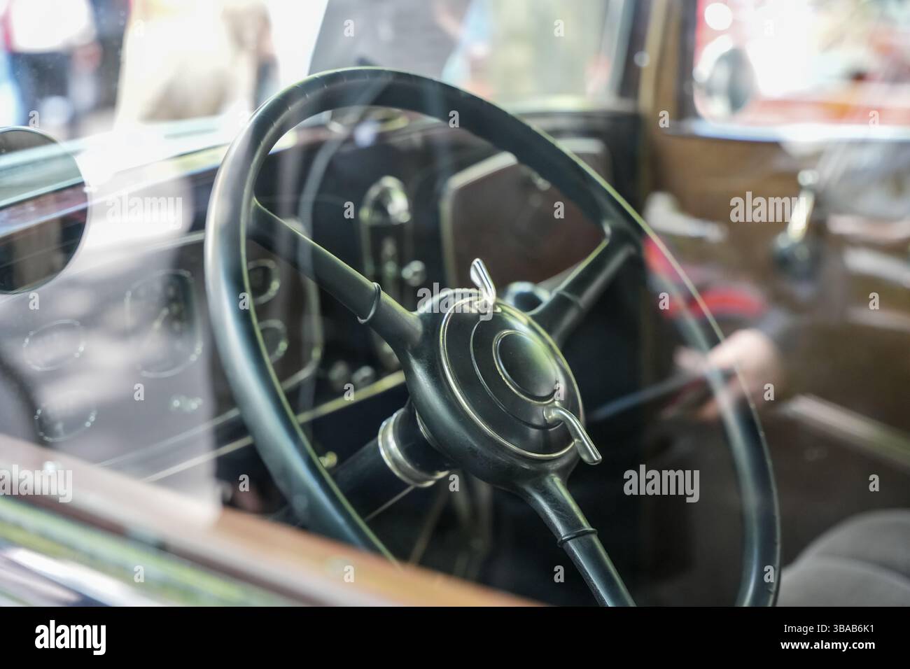 A close-up of a classic steering wheel inside a vintage car, viewed ...