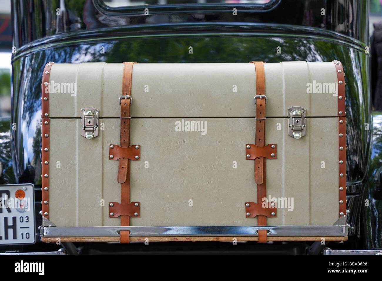 A vintage beige travel trunk with leather straps mounted on the back of ...