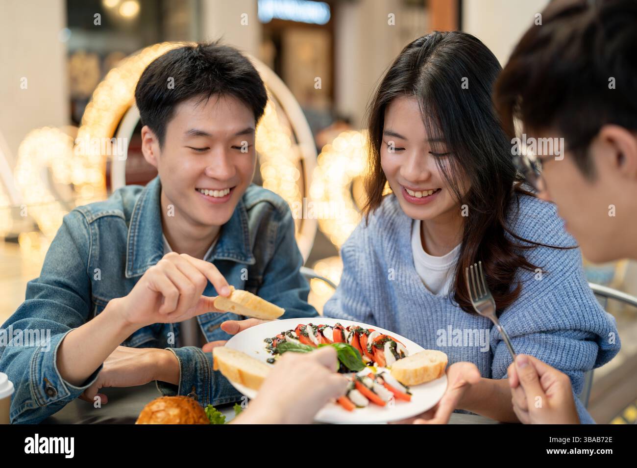 Group of cheerful and joyful young Asian friends enjoying eating food ...
