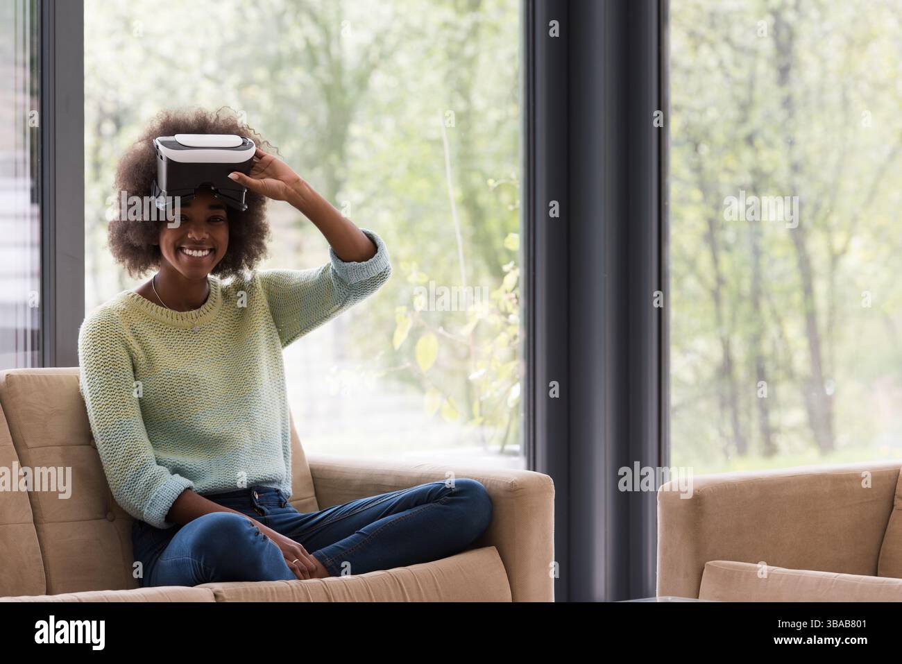 Black woman with afro removing VR headset while sitting with crossed ...