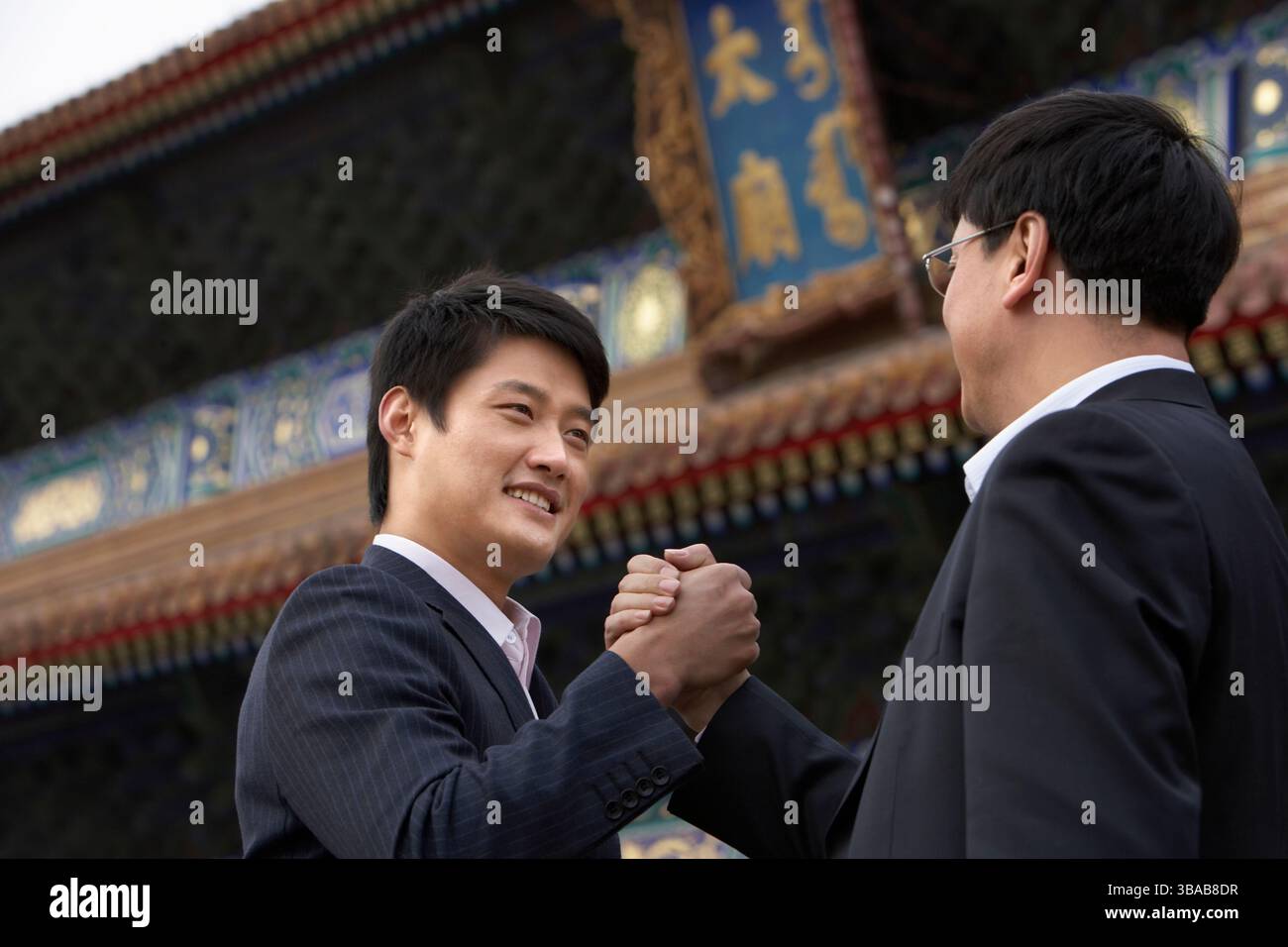 Chinese businessman greeting each other doing manly hand shake standing ...