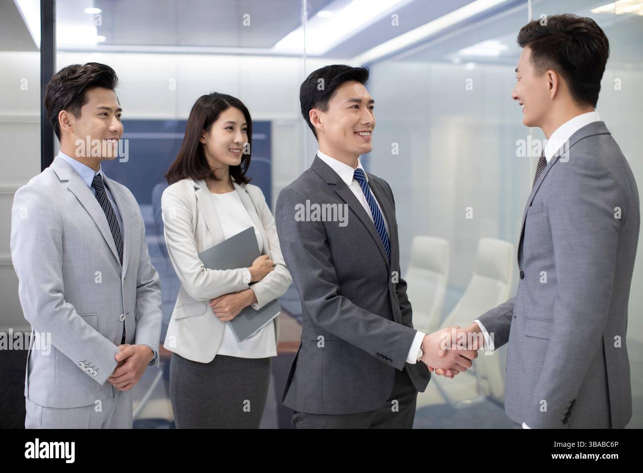Smiling Chinese business people greeting and welcoming business partner ...