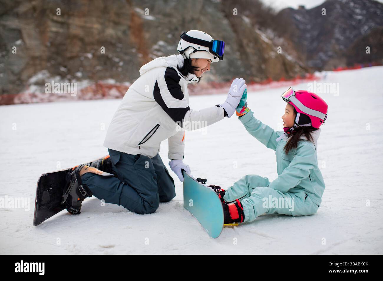 Little Chinese girl learning how to snowboard with her coach Stock ...