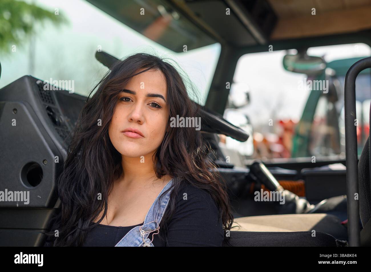Hispanic young model poses in black shirt and blue overalls lean up set ...