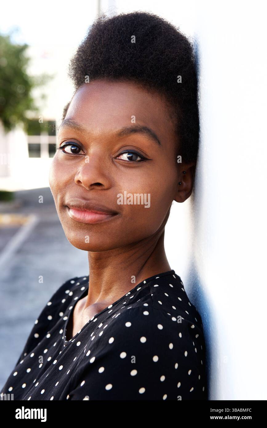 Smiling Black woman leaning on wall on street during daytime Stock ...