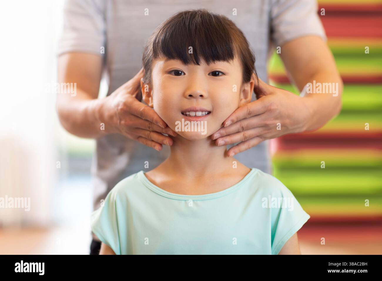 Chinese little girl having physiotherapy with male therapist in gym ...
