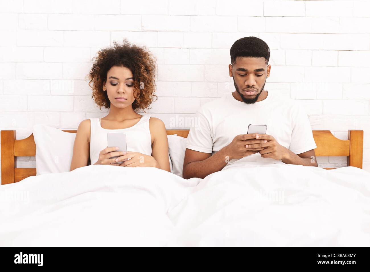 Millennials lifestyle. Young african-american man and woman ignoring each other, using phones in ...