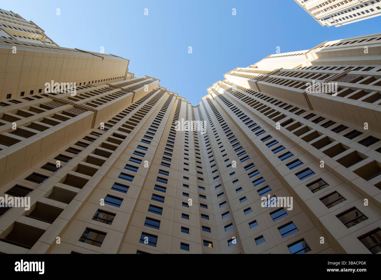 A low-angle view of tall residential buildings reaching towards a clear ...