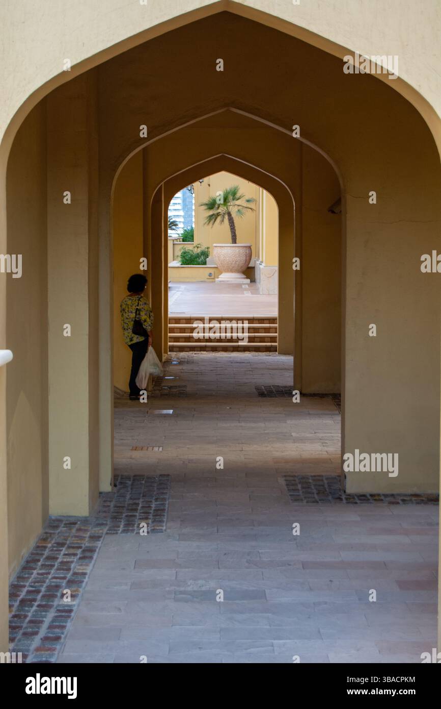 A person standing in a corridor with multiple arches, leading to a ...