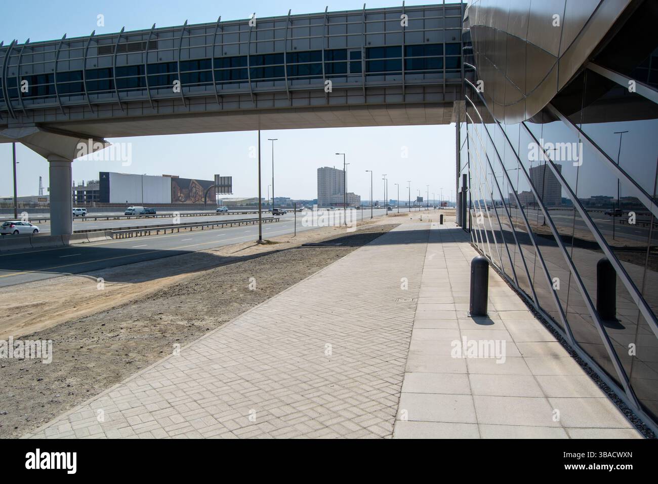 A modern urban scene featuring a wide pedestrian walkway beside a busy ...