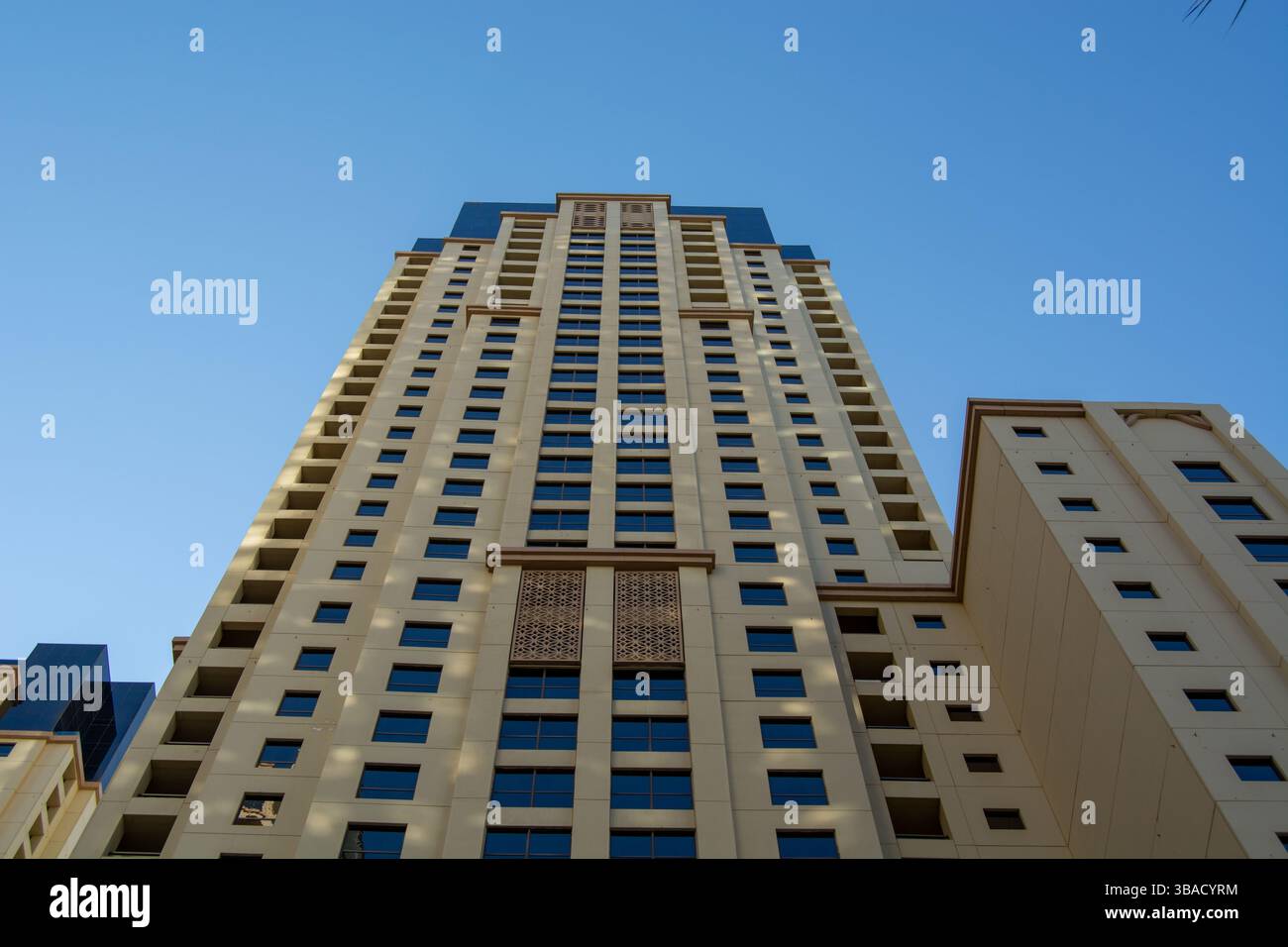 A tall residential building viewed from below against a clear blue sky ...