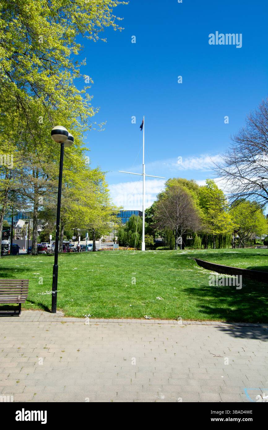 A sunny park scene featuring a green lawn, trees with fresh leaves, and ...