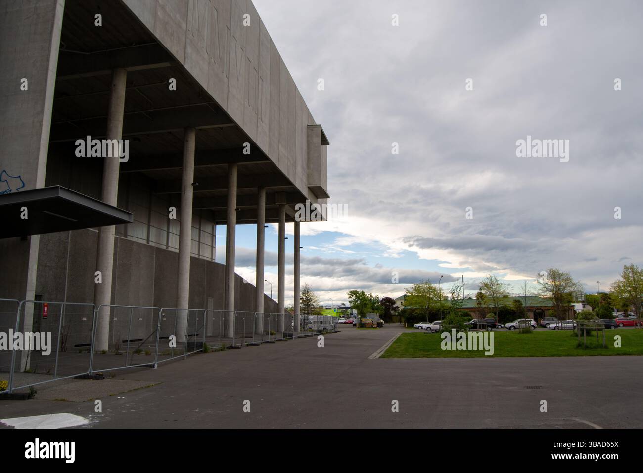 A modern concrete building with tall pillars, set against a cloudy sky ...