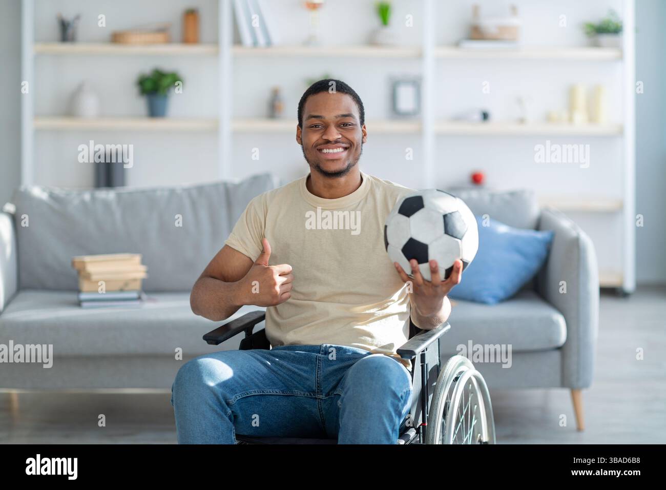 Cheerful disabled black man in wheelchair holding soccer ball and ...