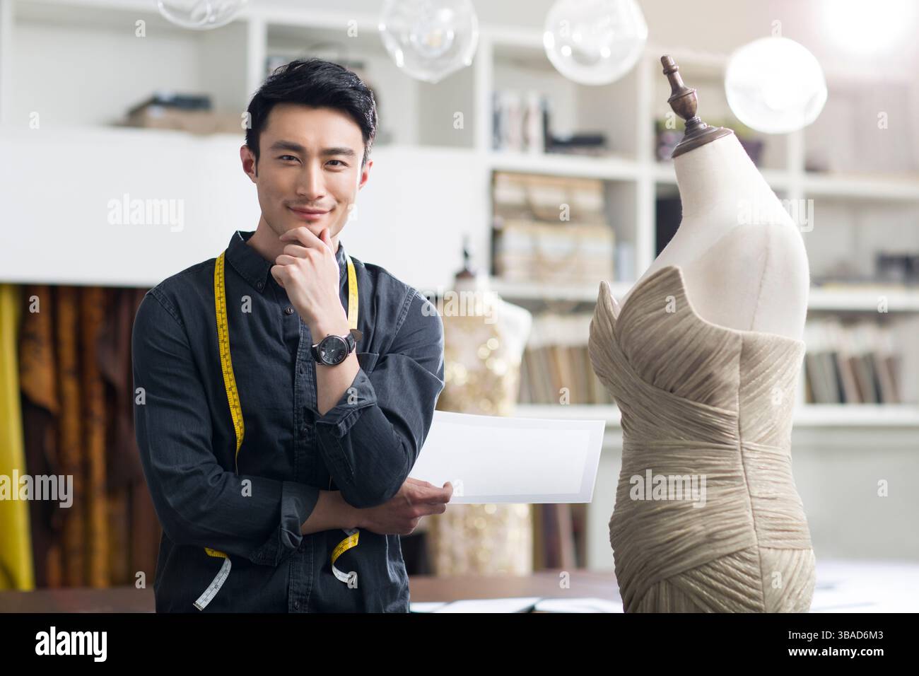 Smiling Chinese male fashion designer wearing black long sleeves and ...