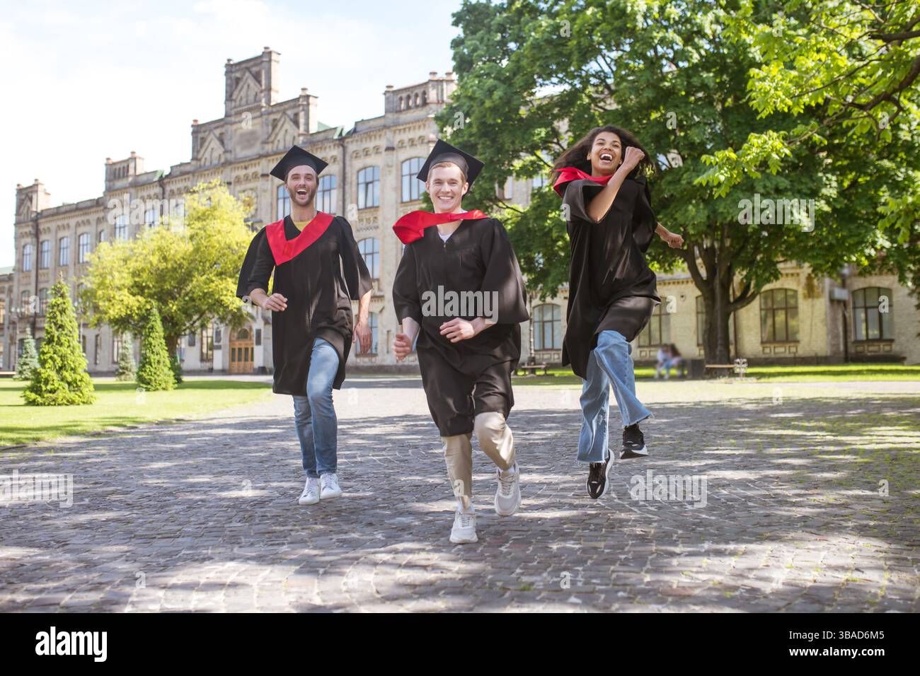 Cheerful Diverse college students running together on school campus on ...