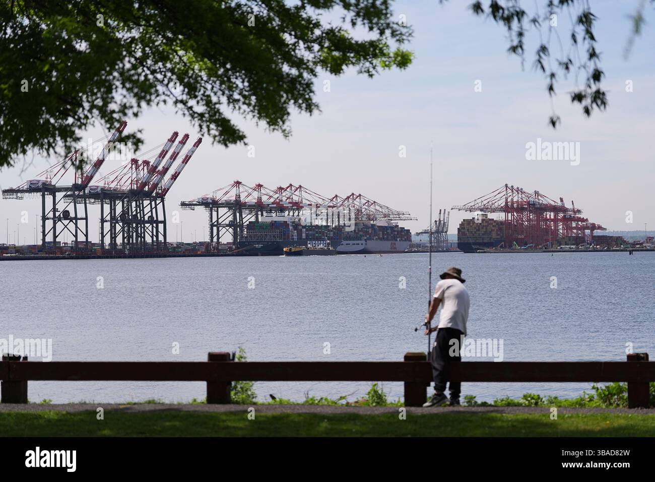A person fishes in view of container ships moored at the port of the ...