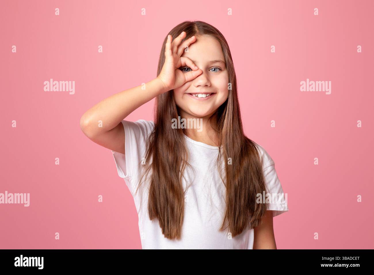 Everything is cool. Smiling kid doing ok sign with hand on eye looking ...