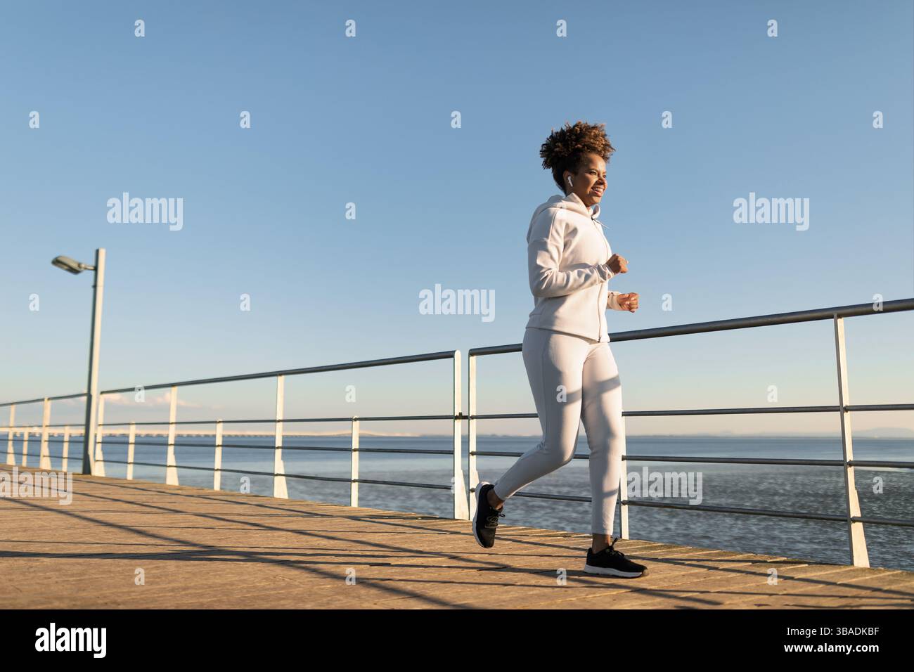 Black woman with afro wearing white workout clothes jogging on ...