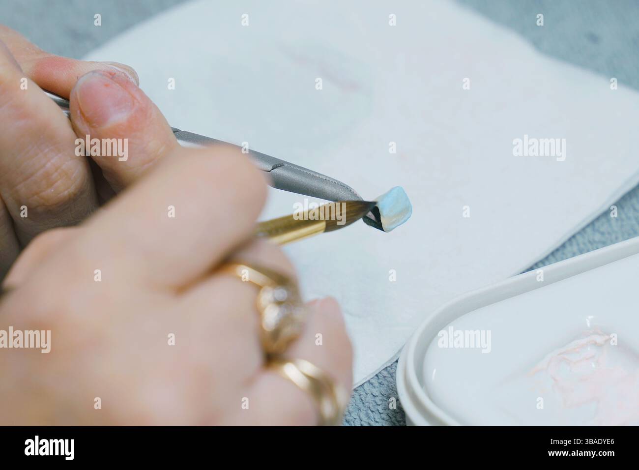 A skilled dental technician meticulously shapes ceramic dentures using ...