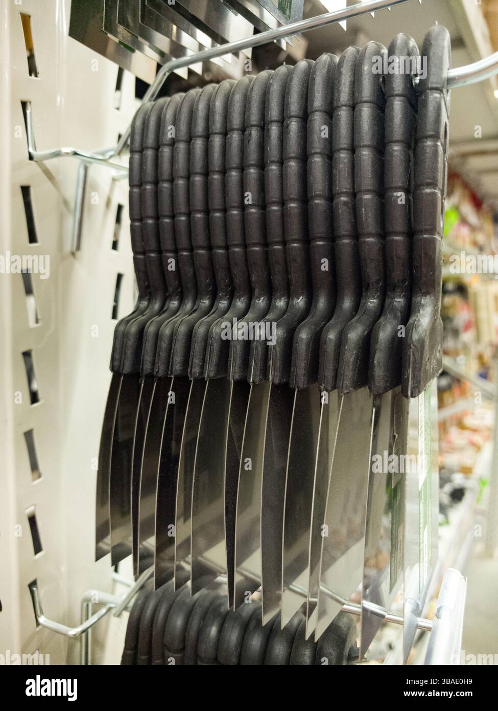 Rows of sharp kitchen knives hang on display in a retail outlet Stock ...