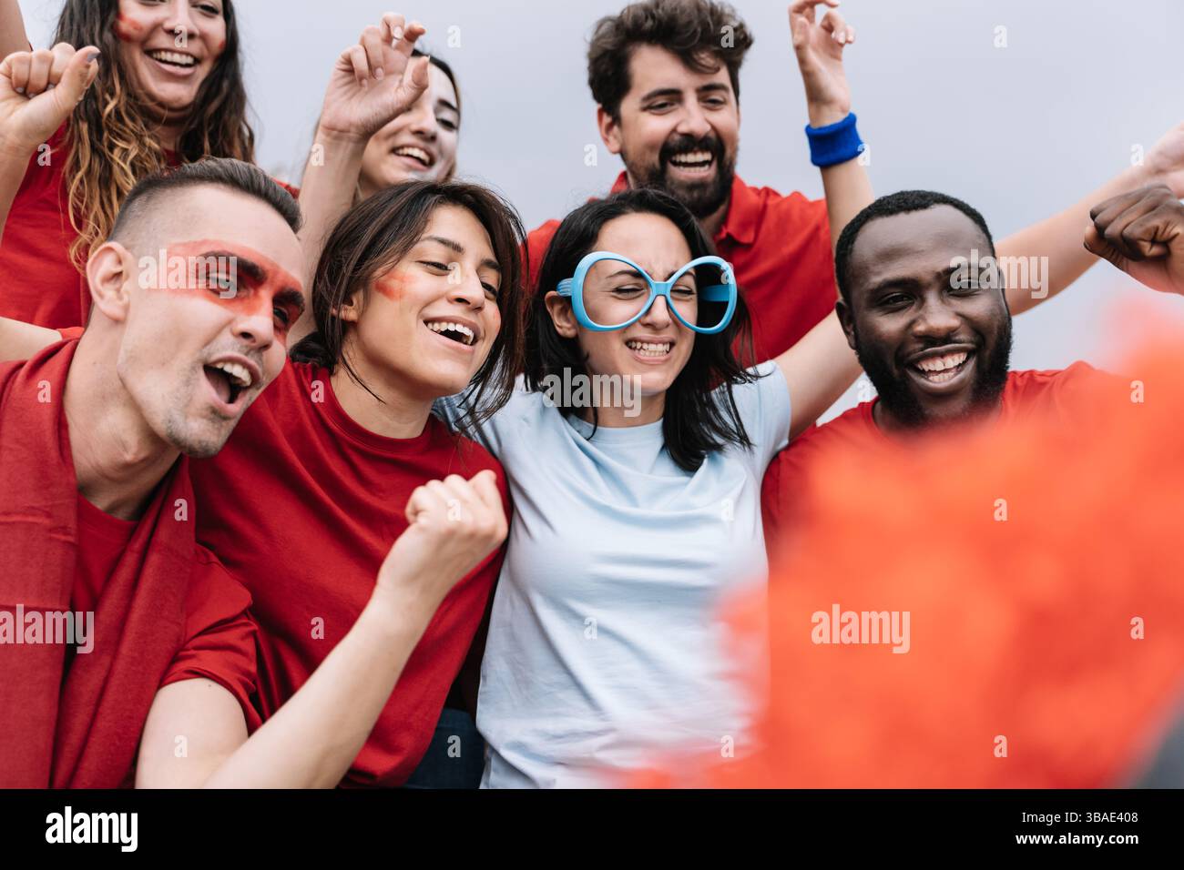 Football fans cheering with raised arms standing close together in ...