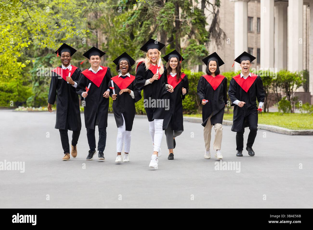 Diverse group of students wearing graduation gowns and caps holding ...