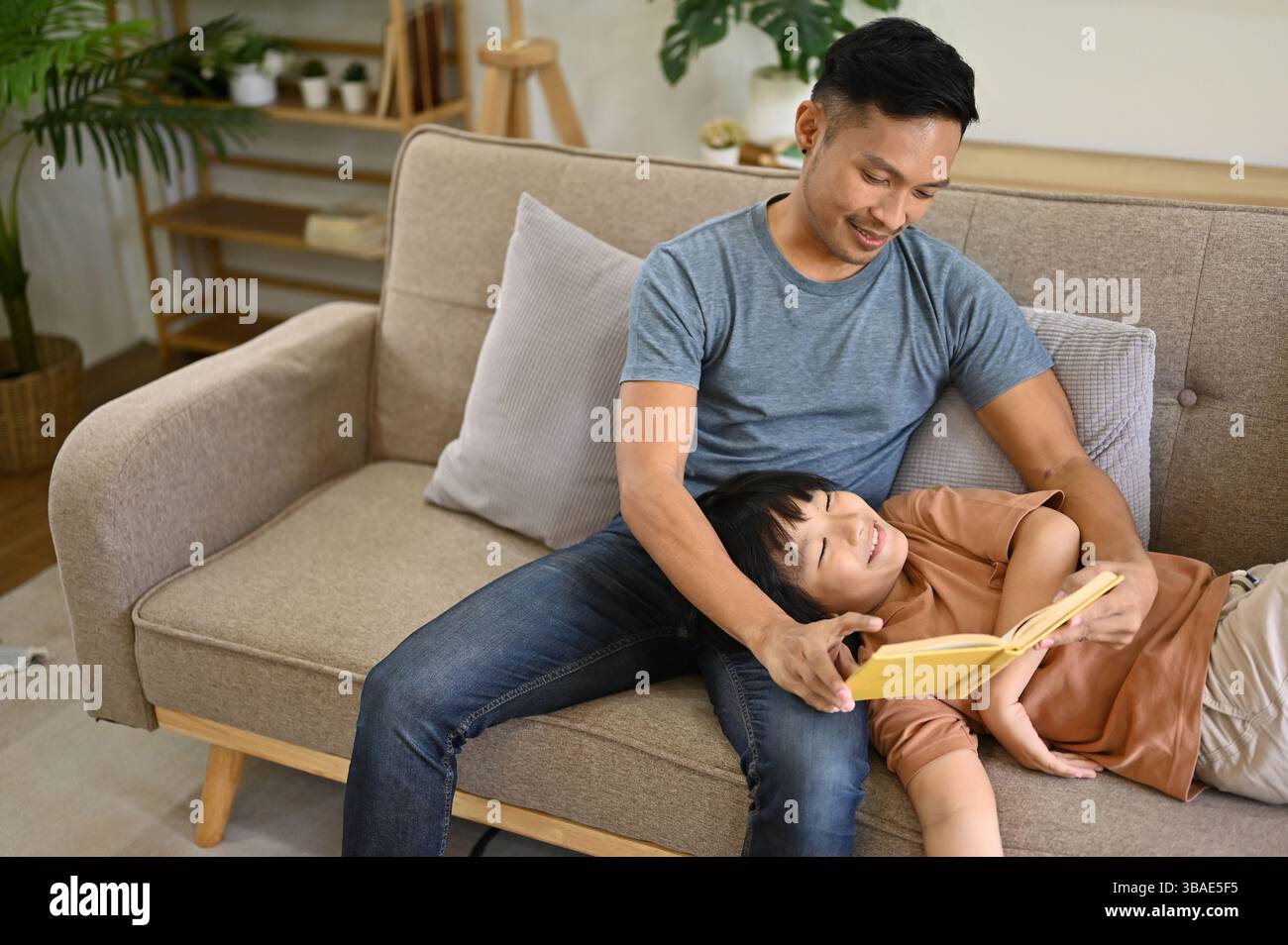 Caring and kind Asian dad telling story or reading a book with his son ...