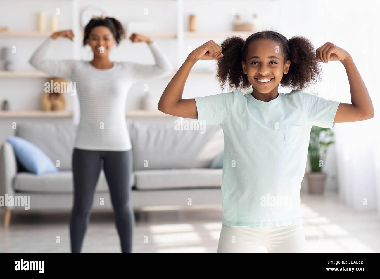 Cheeful teen black girl in sportswear showing her muscles, cute ...