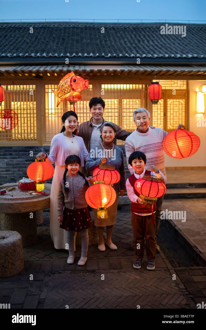 Cheerful Chinese family standing together holding lanterns celebrating ...