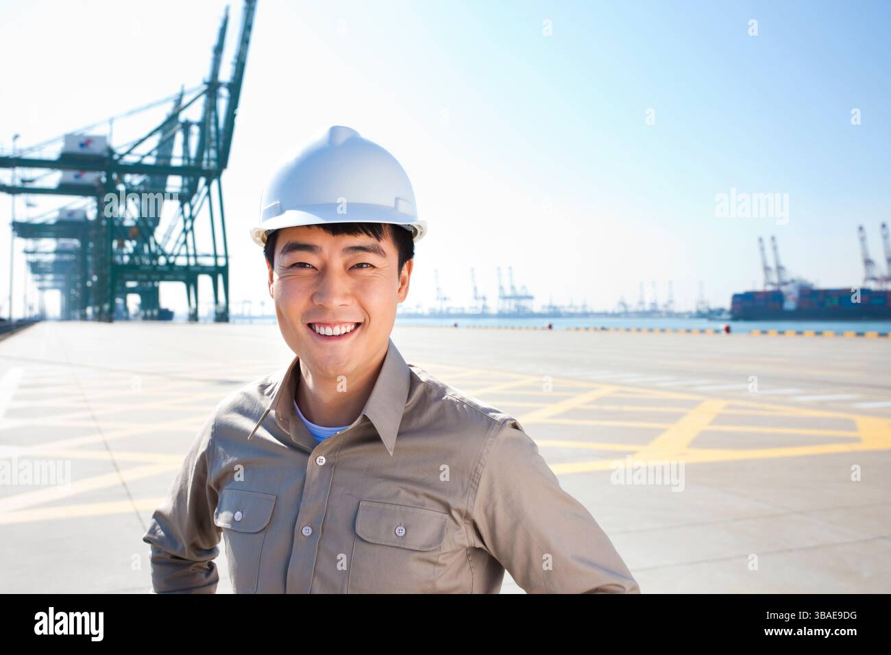 Male Chinese shipping industry worker with hands on hips with shipping ...