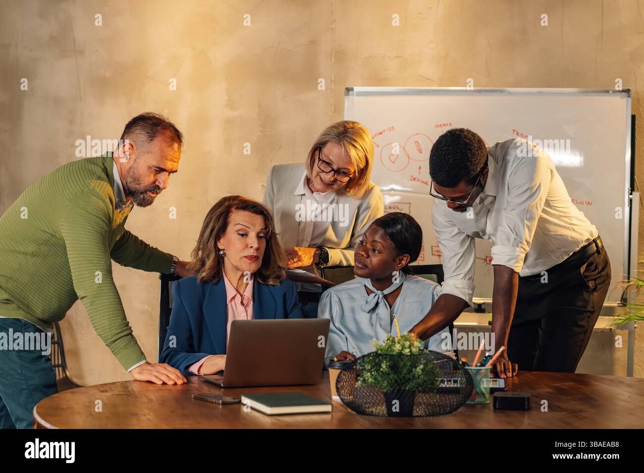Senior female boss sitting at conference room and typing on a laptop ...