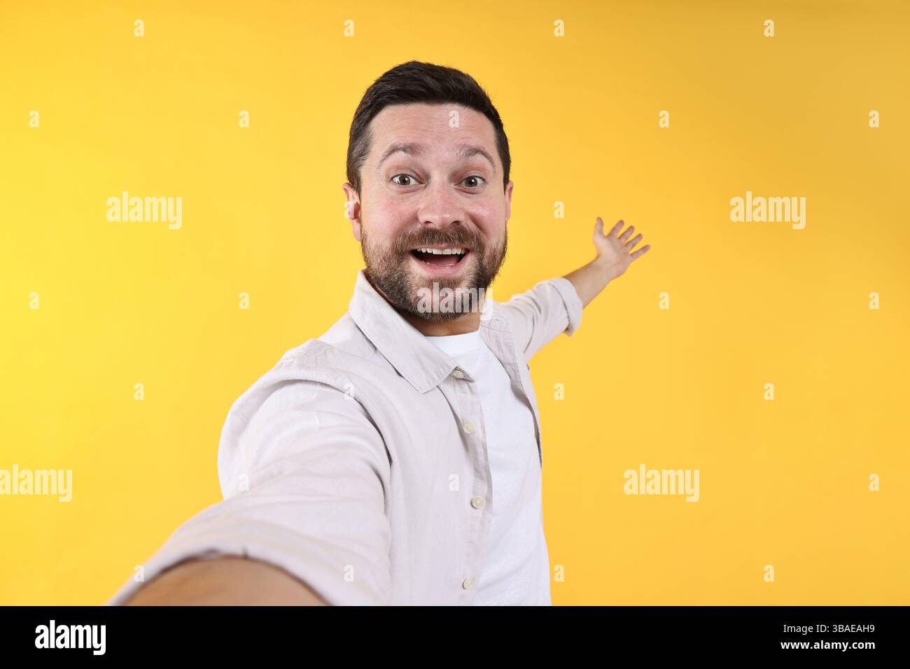 Happy man welcoming friends or guests on yellow background, view ...