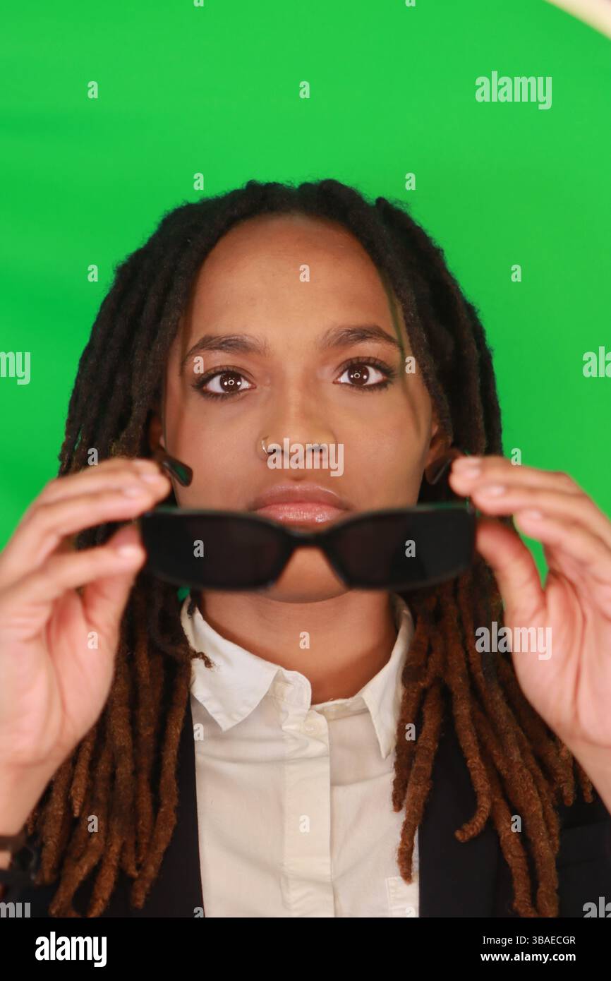 Black woman of Afro-Caribbean descent with dreadlocks dressed in formal business attire putting ...