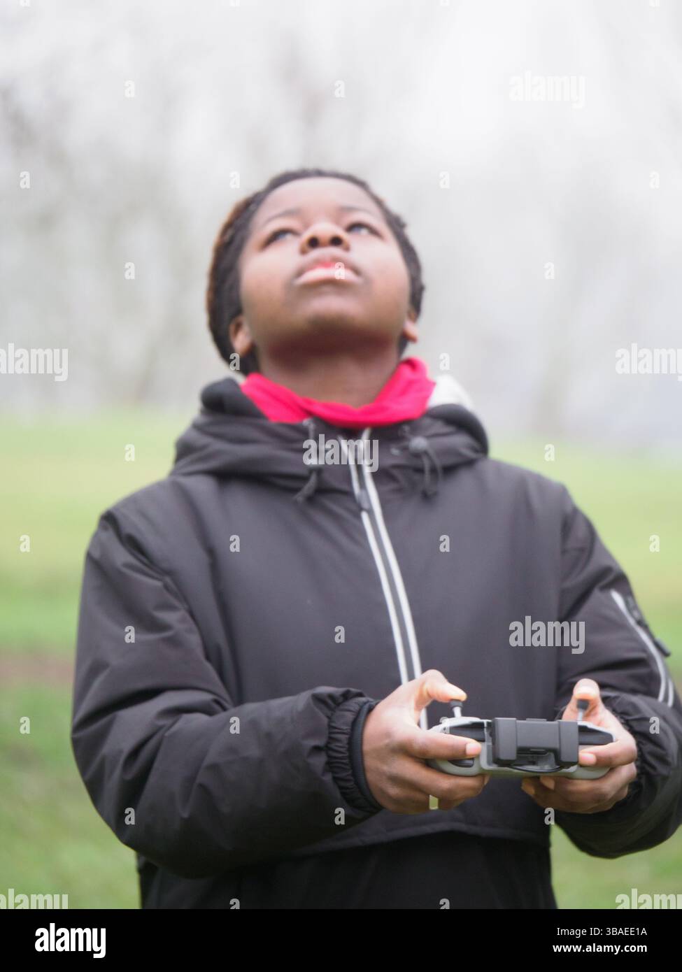 Black female teenager with dreadlocks using drone controller standing ...