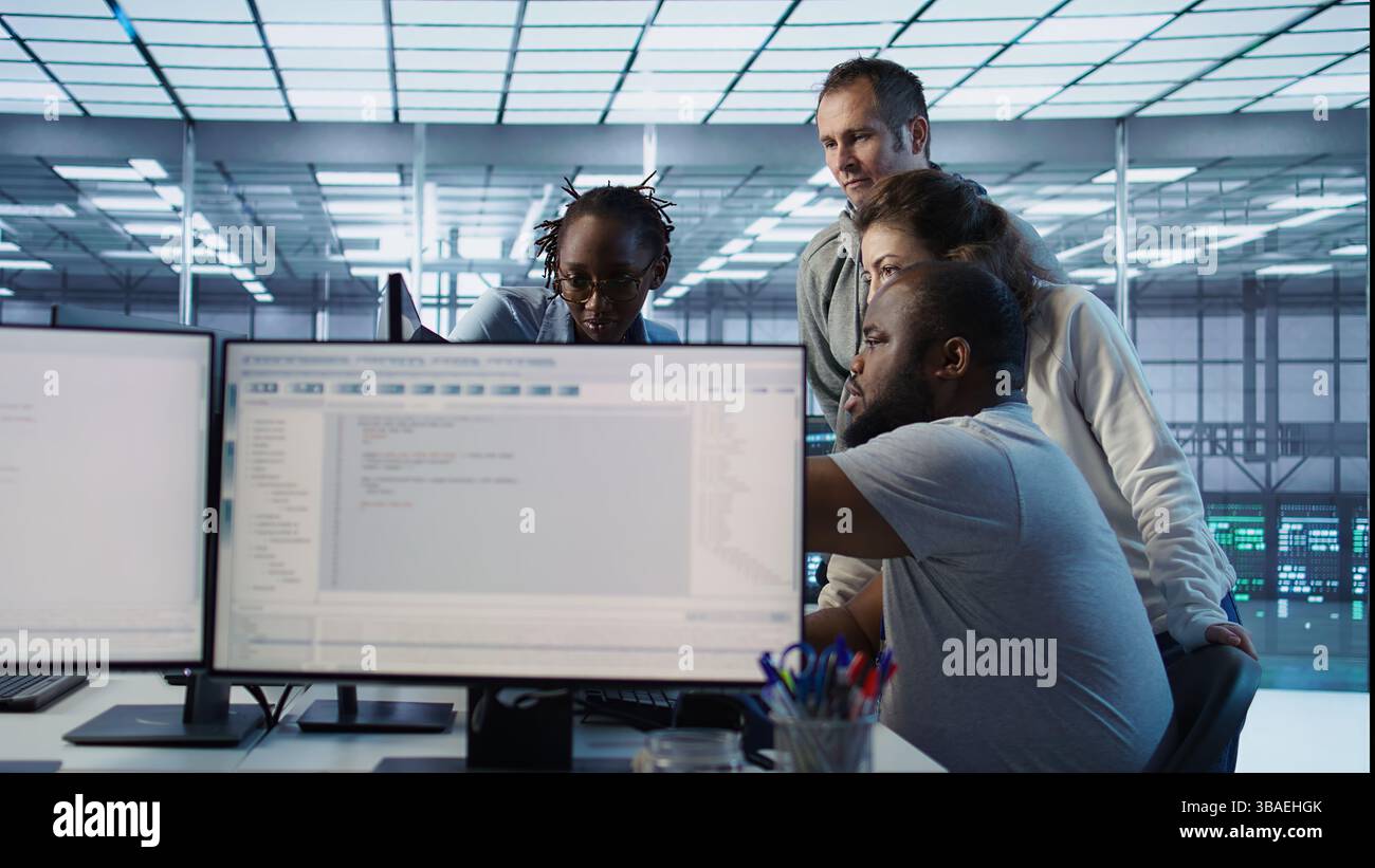 Multiethnic team of engineers working in server hub, using PCs to analyze data. Multiracial ...