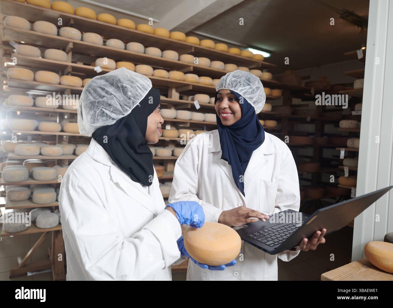 Smiling Middle Eastern female workers in hijab and white uniforms ...