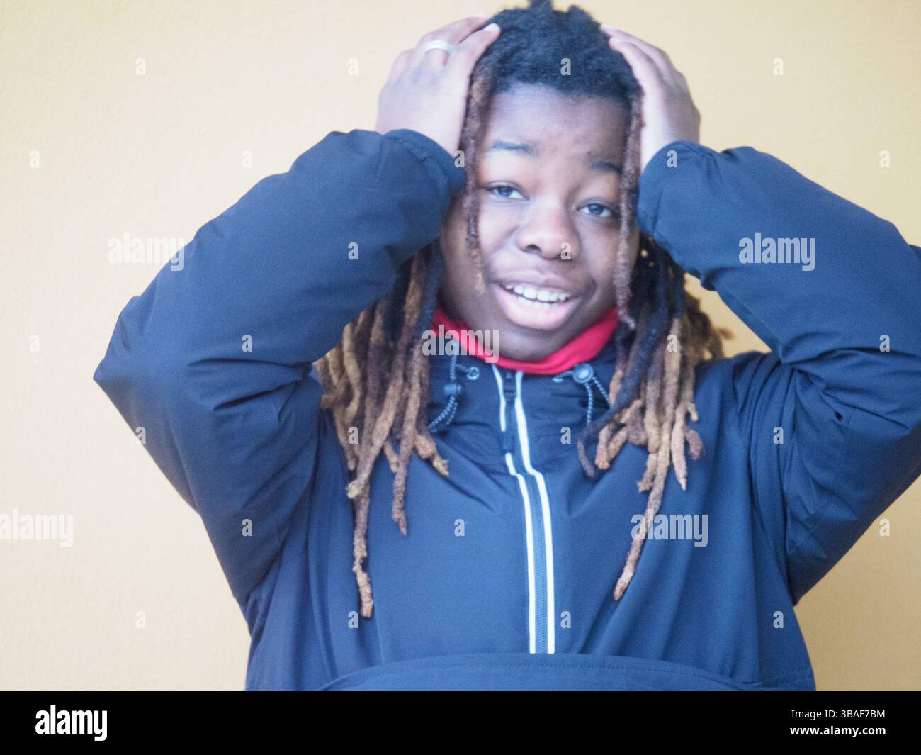 Black female teenager with dreadlocks putting hands over head while ...