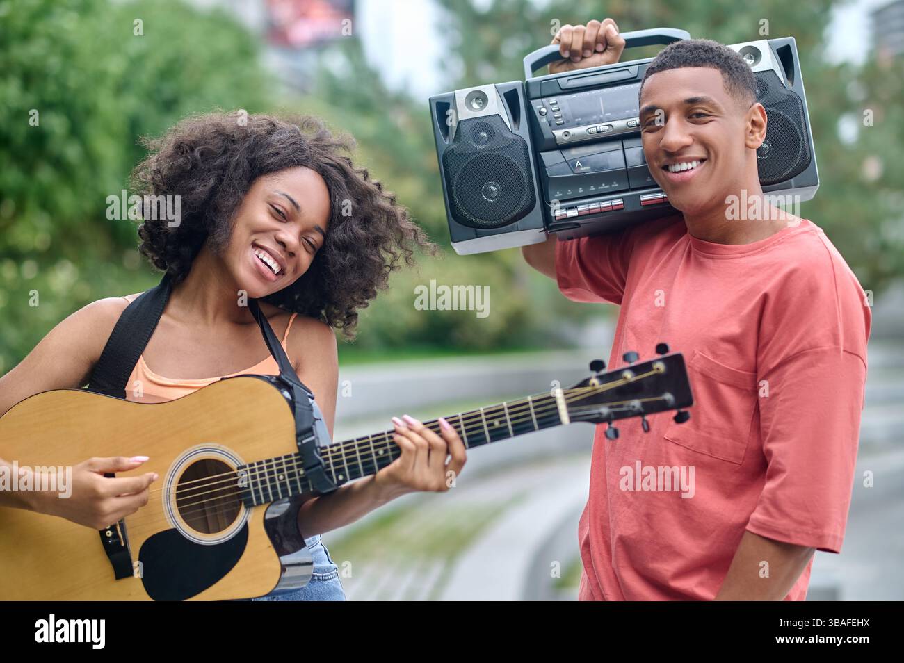 Best time. Happy dark-skinned girl with guitar and guy holding record ...