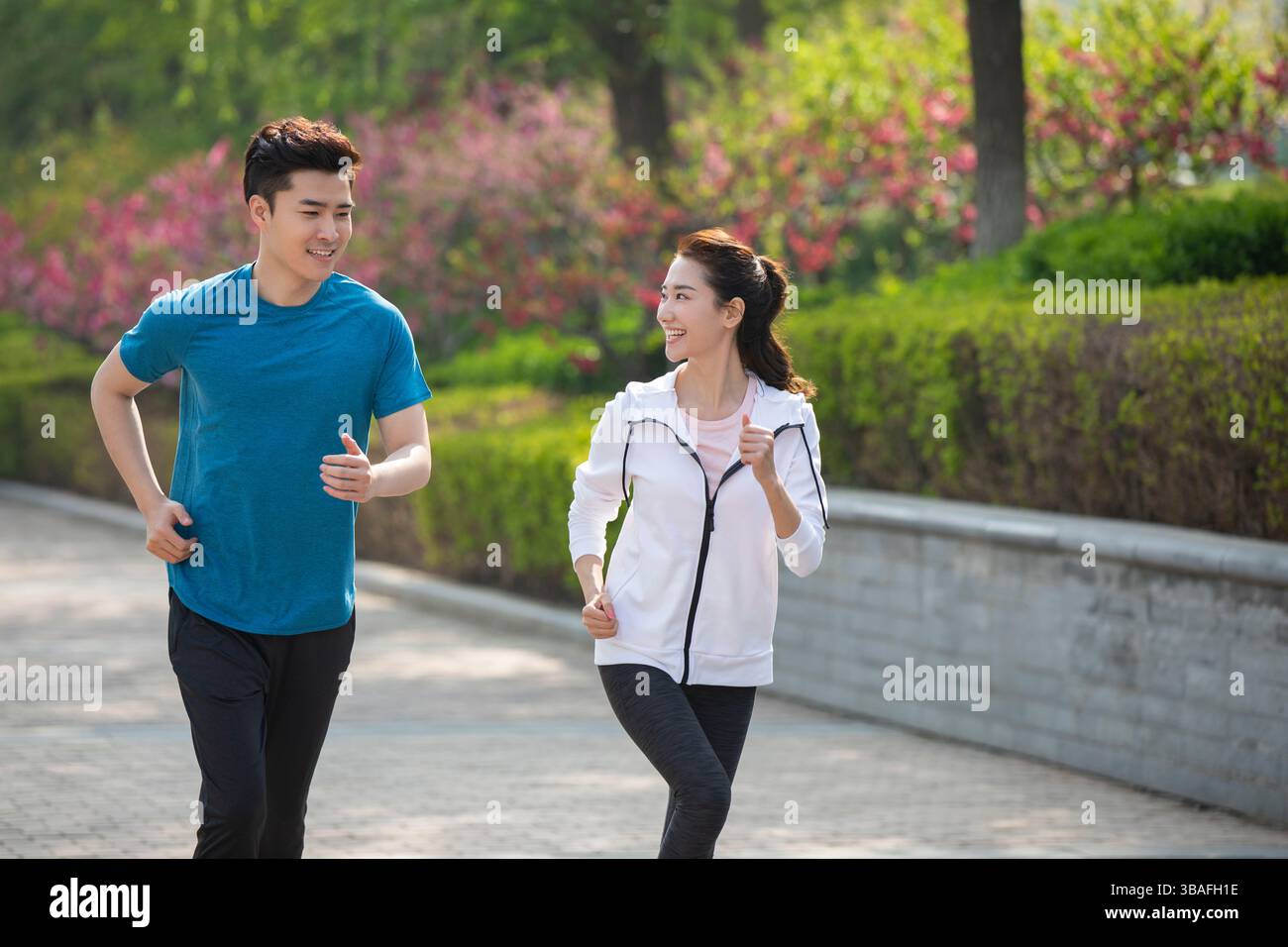 Smiling Chinese couple in fitness wear looking at each other while ...