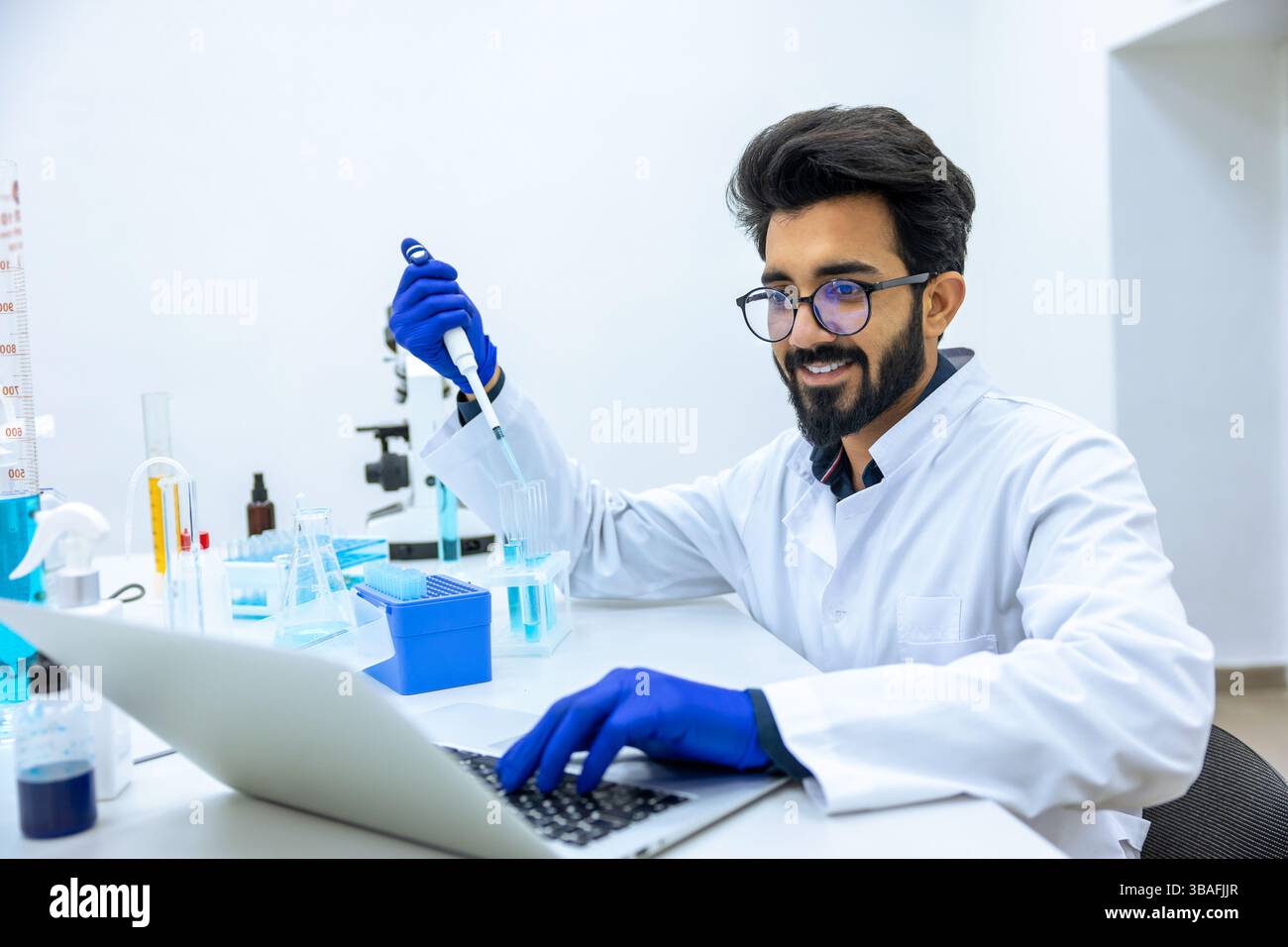 Man scientist in lab coat holding glass-dropper with reagents, making ...