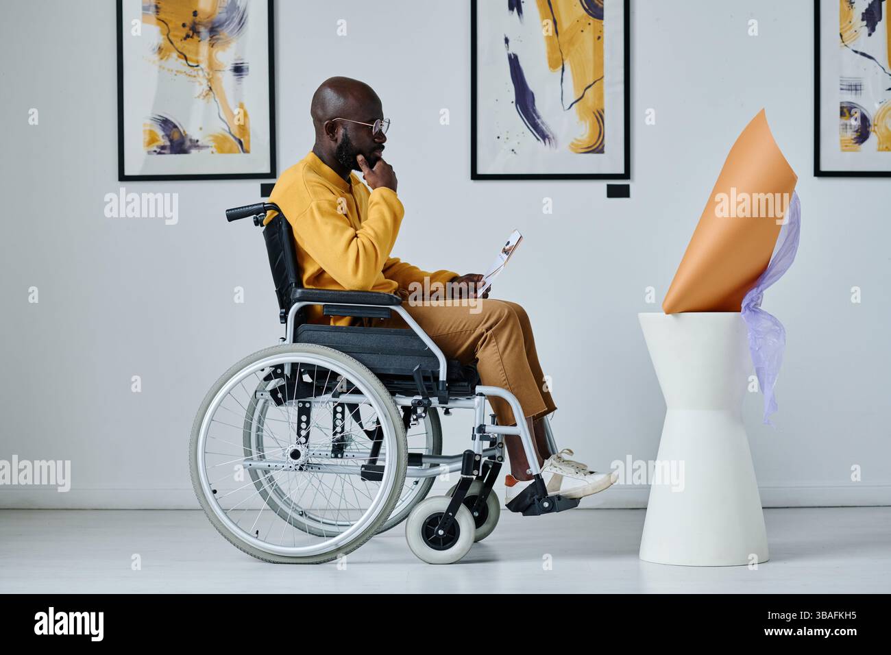 African young man with disability examining booklet while visiting ...