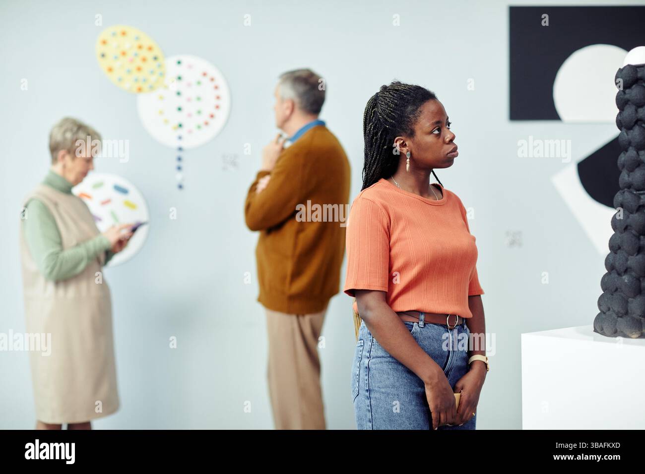 Group of three people visiting exhibition in museum of modern arts ...