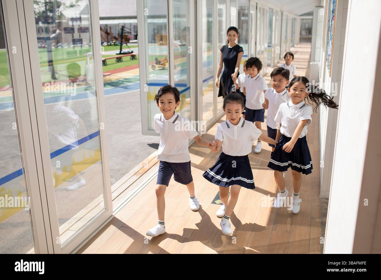 Chinese children with female teacher running in school hallway Stock ...