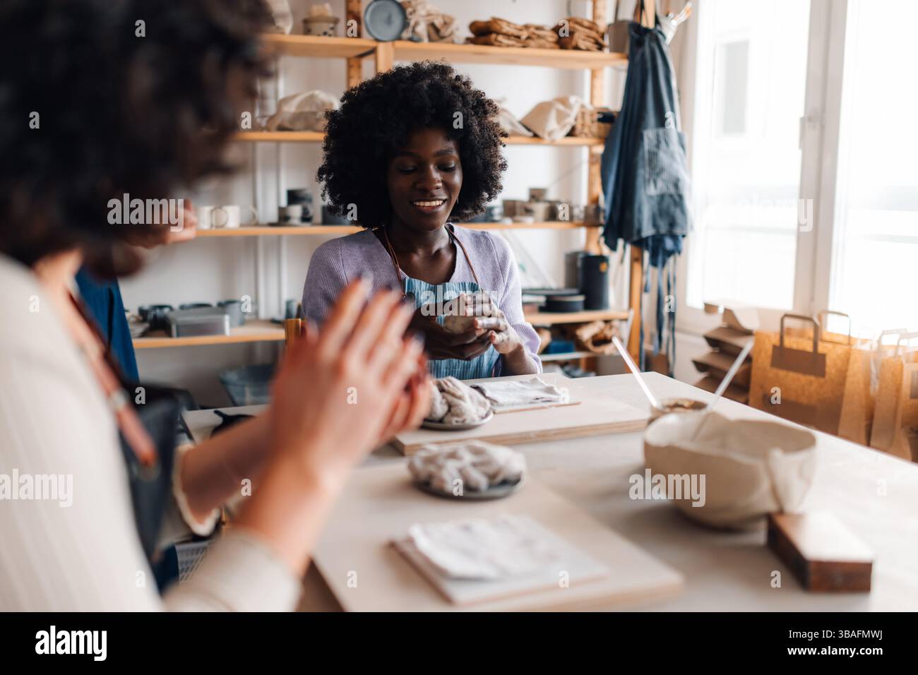 Portrait of a multicultural pottery class student sitting at workshop ...